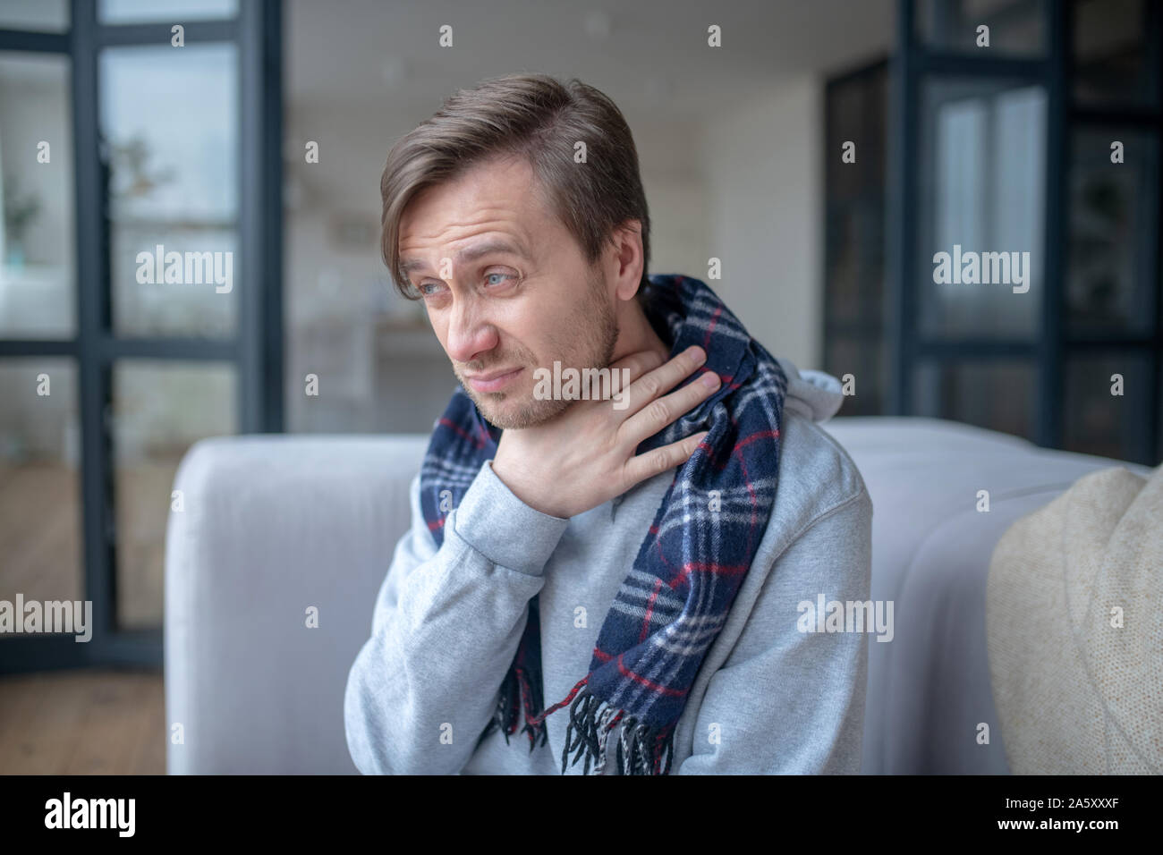 Man touching his neck while having strong cough Stock Photo - Alamy