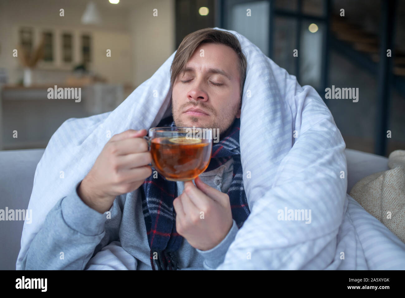 Sick man smelling lemon while drinking hot tea Stock Photo - Alamy