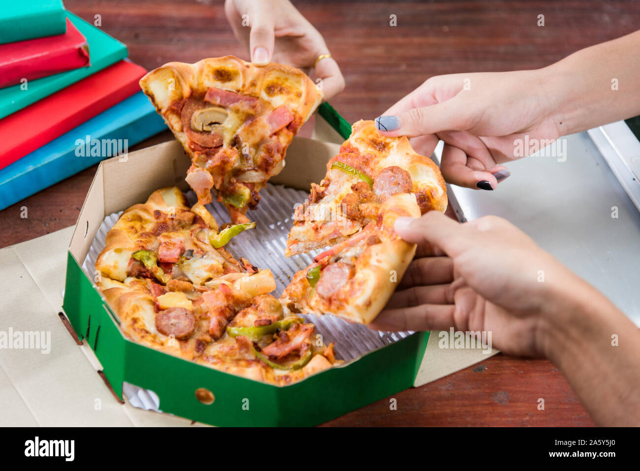 Hands taking pizza slices from green box Stock Photo - Alamy