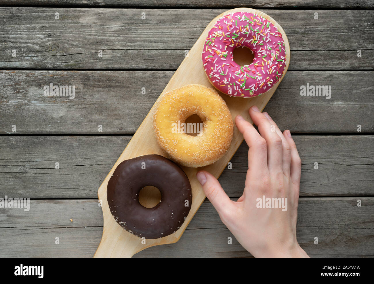three donuts on a wooden board background with blank space Stock Photo ...