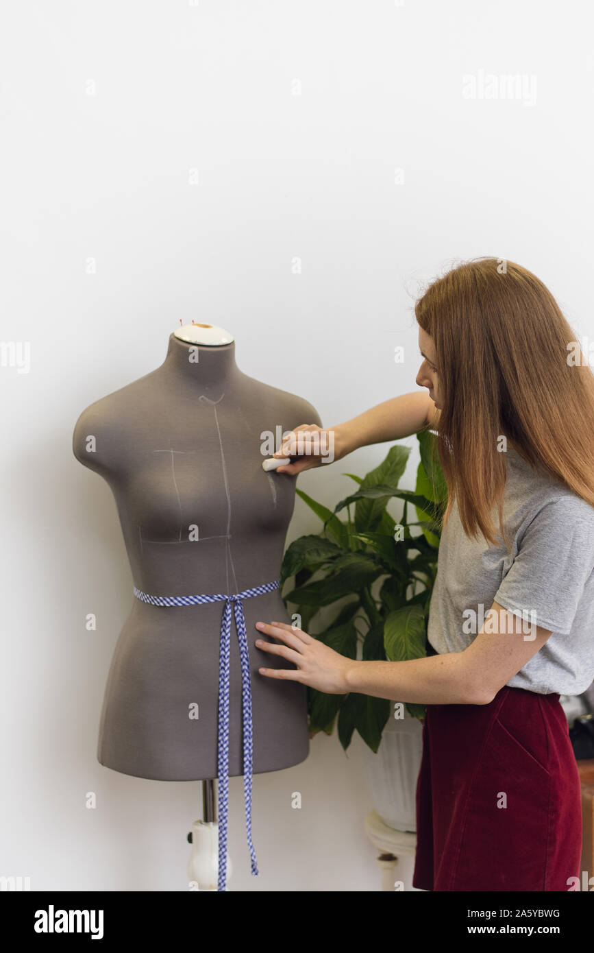 Seamstress takes measurements with chalk on a mannequin in the office ...