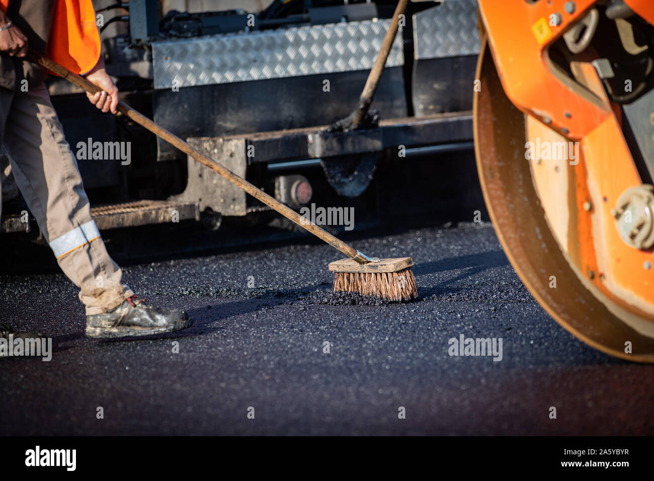Worker with roller compacting asphalt on a road Stock Photo - Alamy