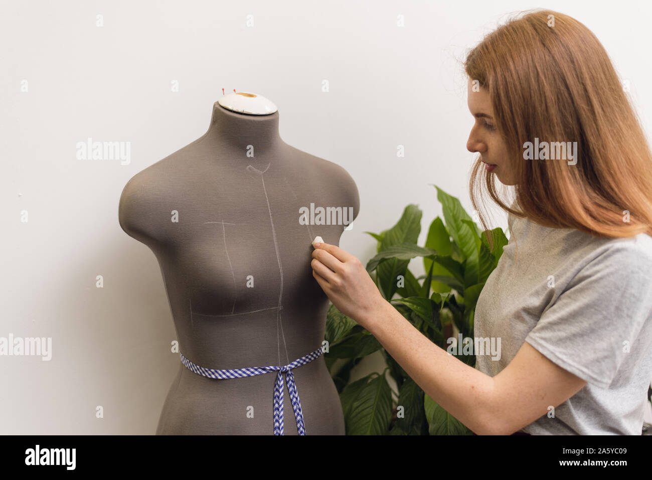 Seamstress takes measurements with chalk on a mannequin in the office ...