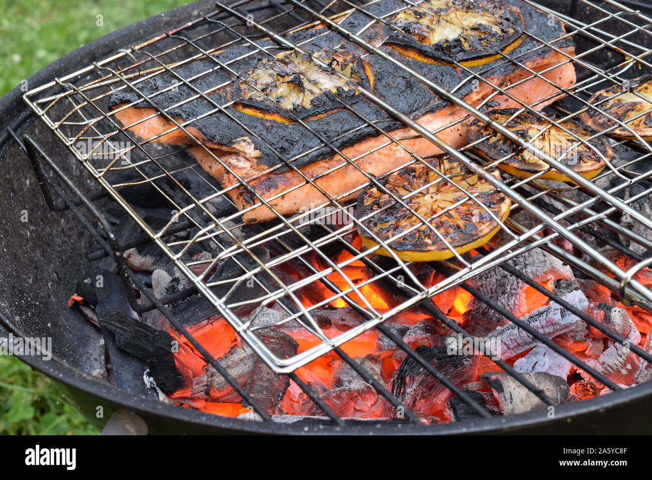 Grilling whole salmon fillets with gridiron. Fish and lemon slices are ...