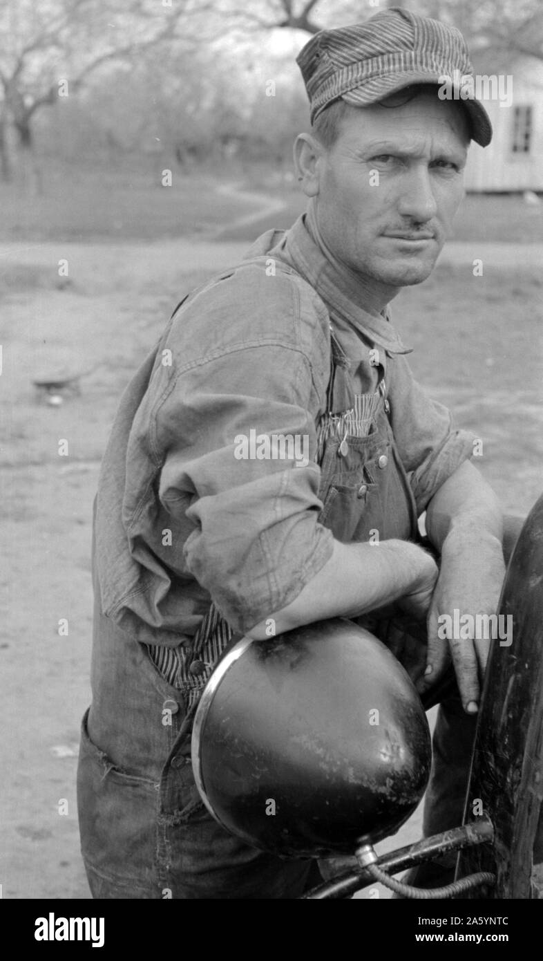White migrant worker leaning on headlamp of his car near Harlingen ...