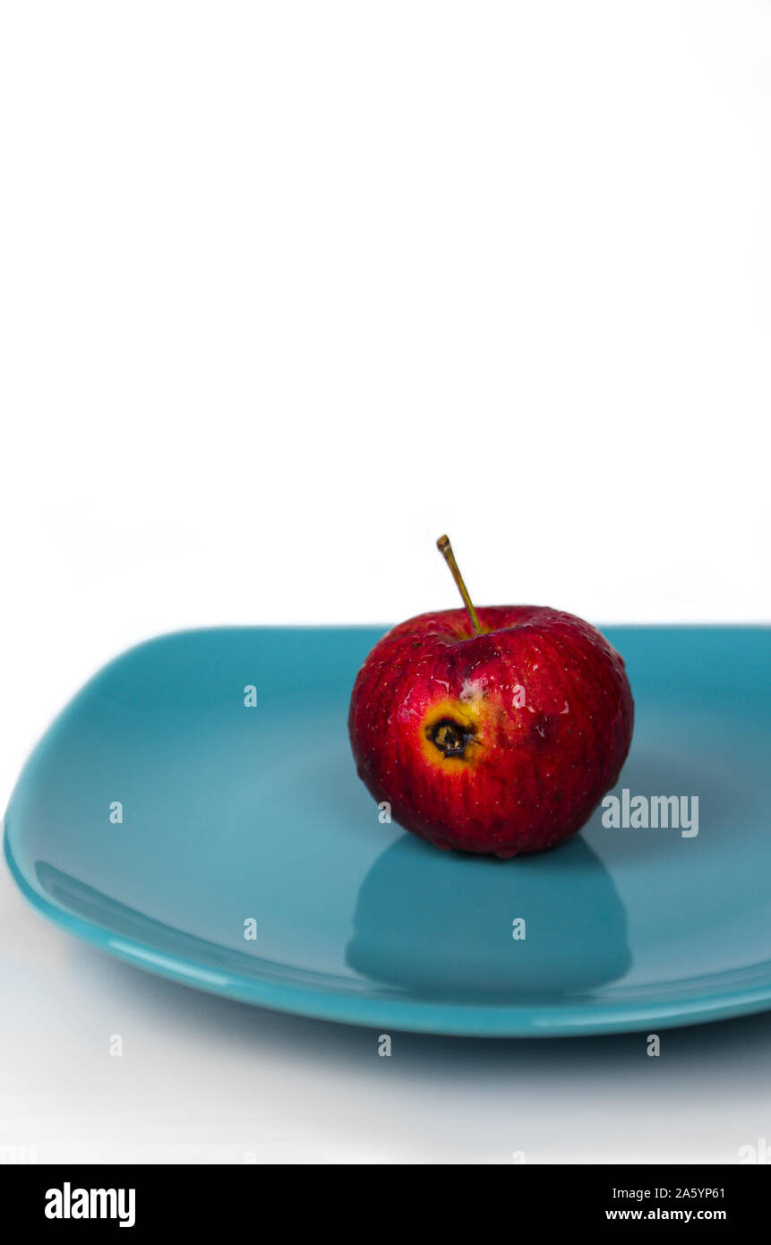 Rotten red apple on a turquoise plate, on white background Stock Photo ...
