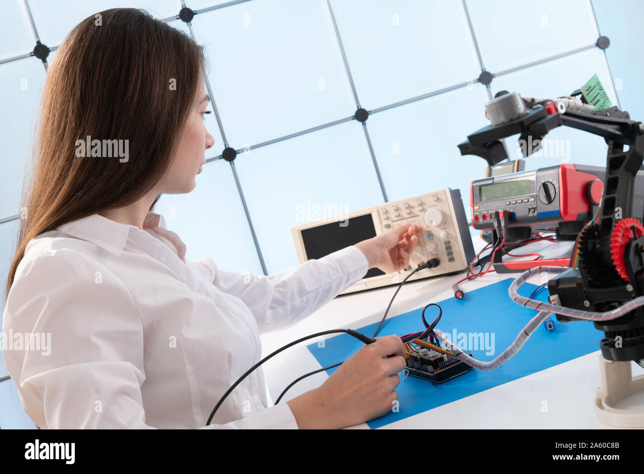 A young woman writes an algorithm for the robot arm. Science Research ...