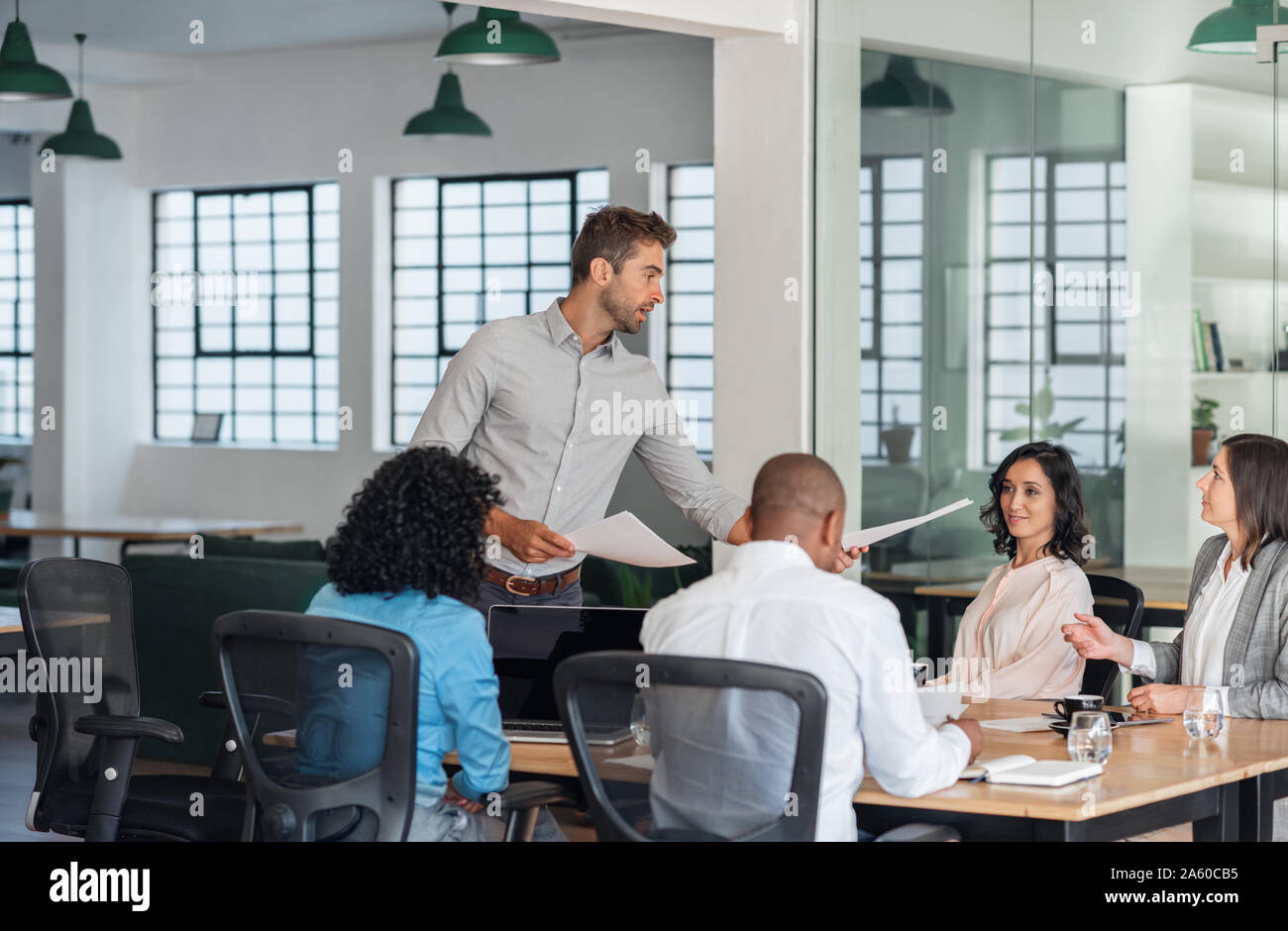 Businessman handing out paperwork during an office meeting Stock Photo ...