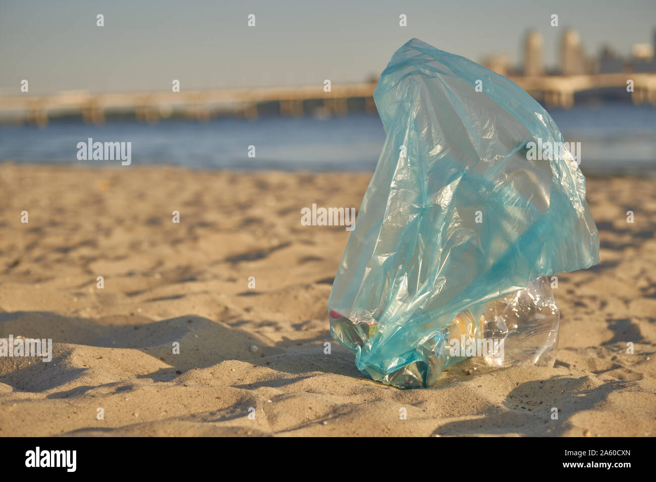 Blue bag with garbage lies on a beach of a picturesque river. Cleaning ...