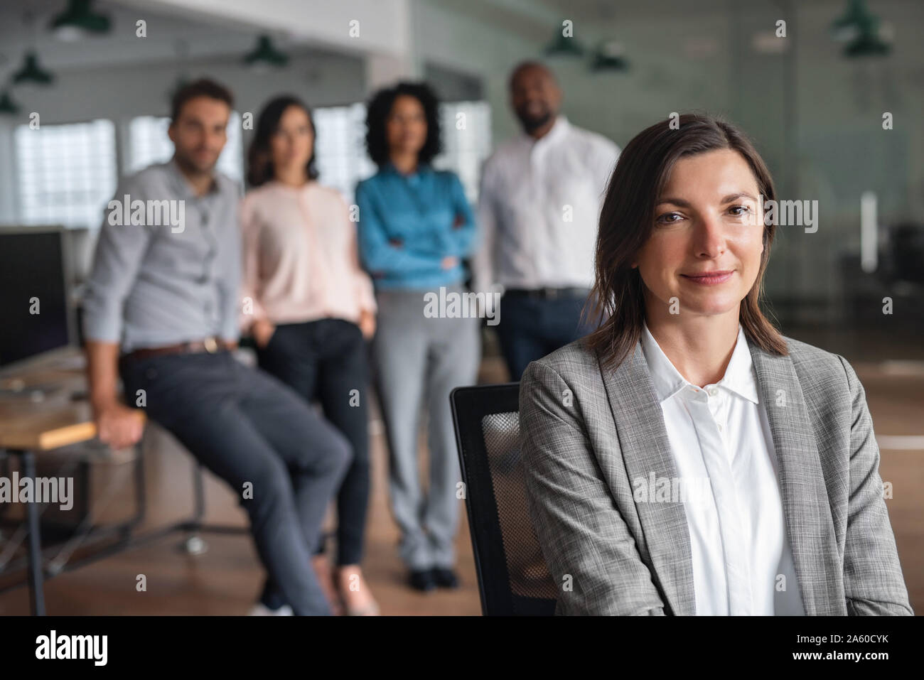 Businesswoman smiling with coworkers standing in the background Stock ...