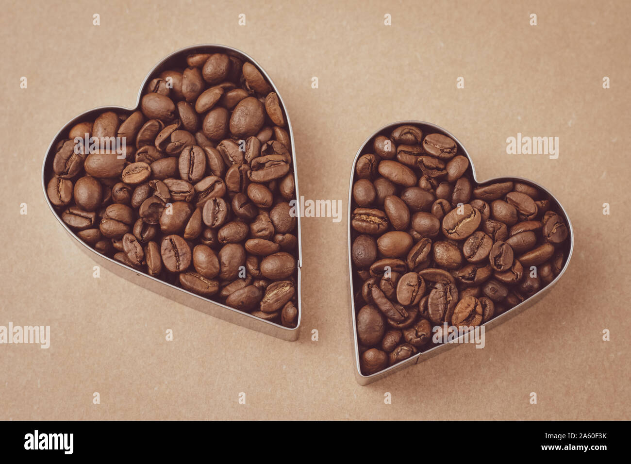 Two hearts of coffee beans on brown background. Craft paper. Art design ...