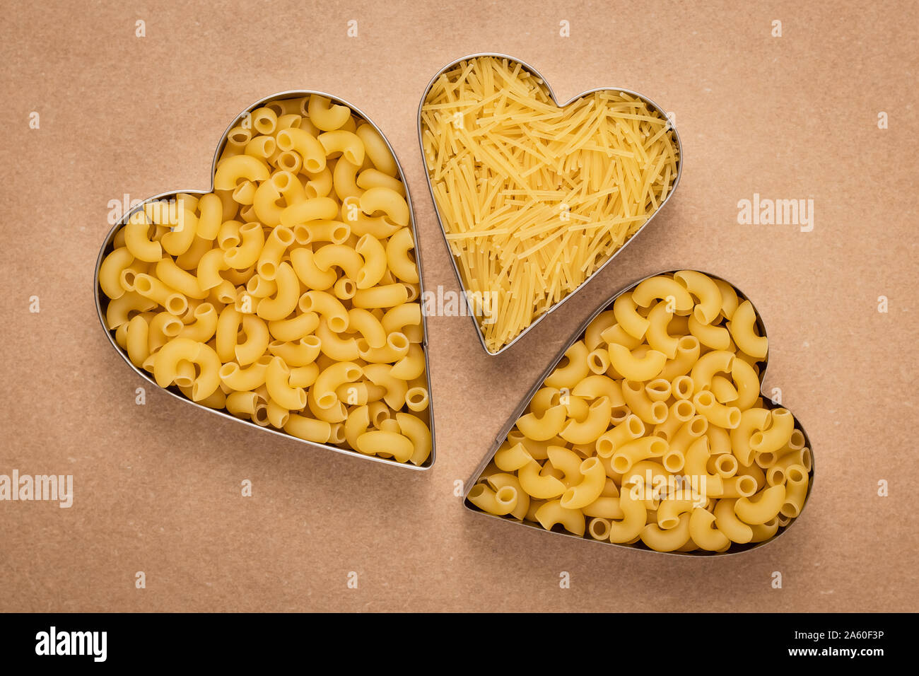 Three hearts of pasta on brown paper background. Art design. Vintage ...