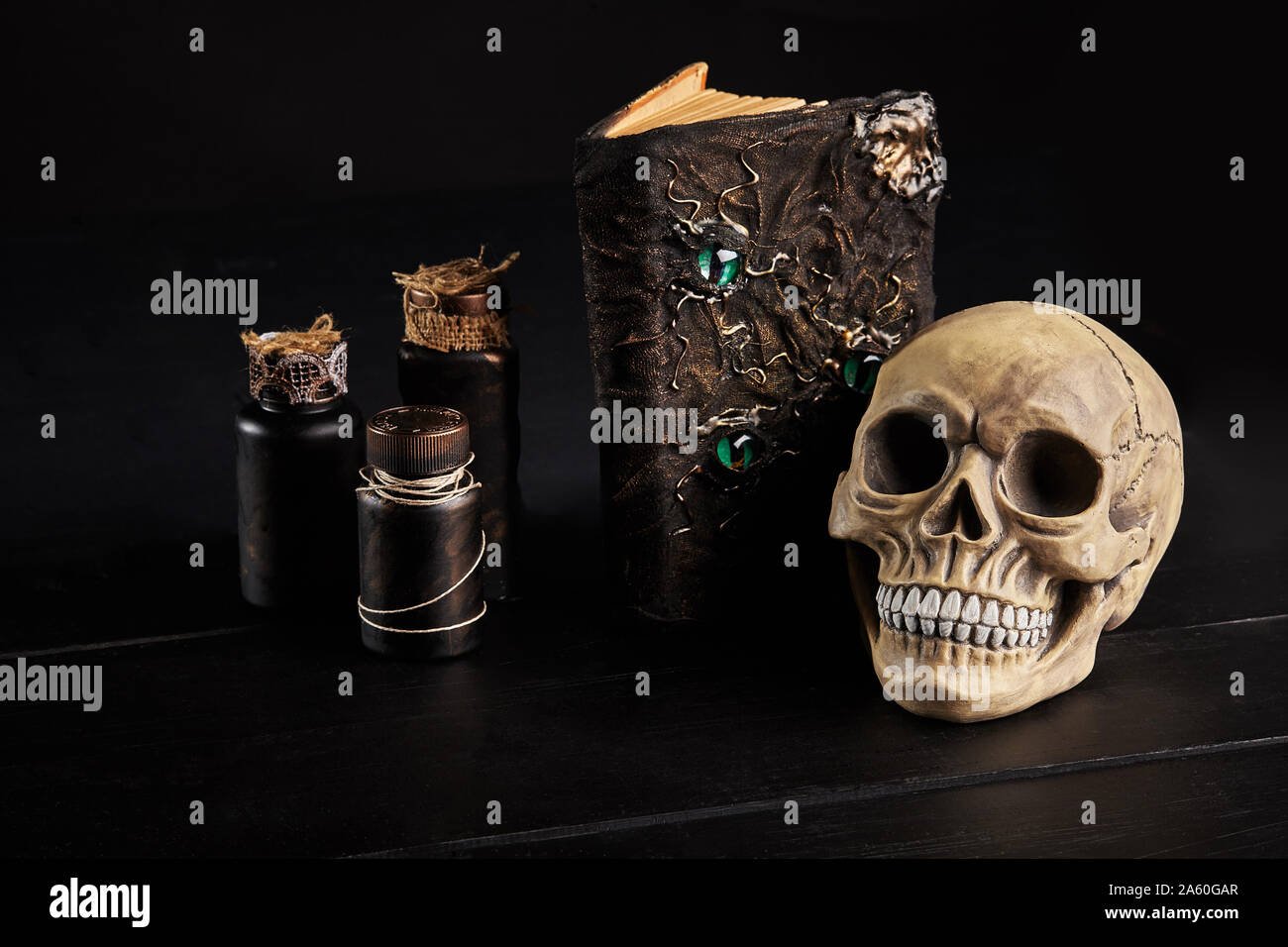 Realistic model of a human skull with teeth, book with spells, jars of ...