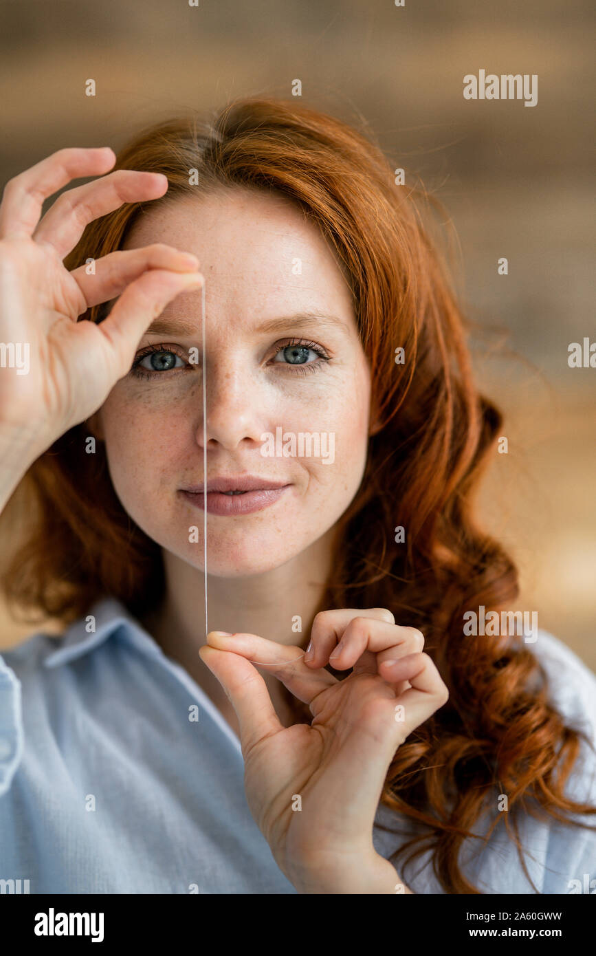 Portrait of redheaded woman holding thread of dental floss Stock Photo ...