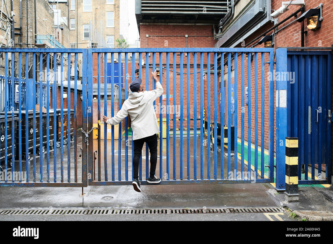 Back view of man climbing gate Stock Photo - Alamy