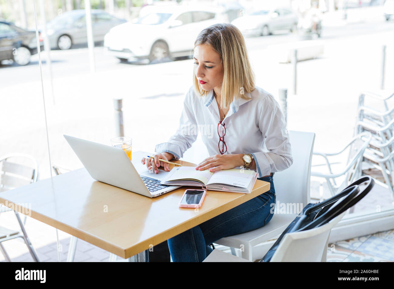 Young woman with laptop and notebook on table in a cafe Stock Photo - Alamy