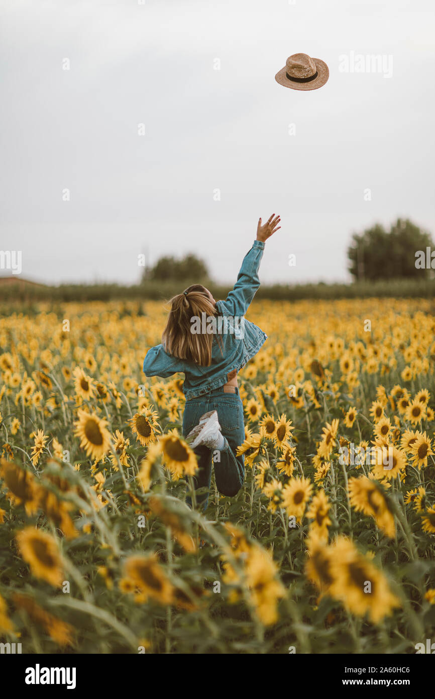 Rear View of young woman with blue denim jacket throwing a hat in a ...
