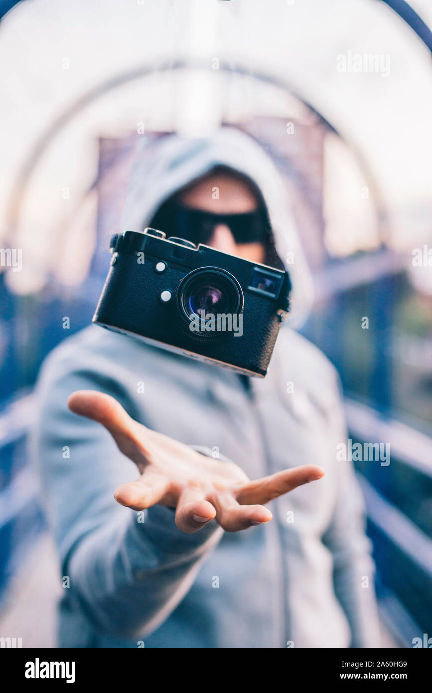 Man with hood throwing a vintage camera Stock Photo - Alamy