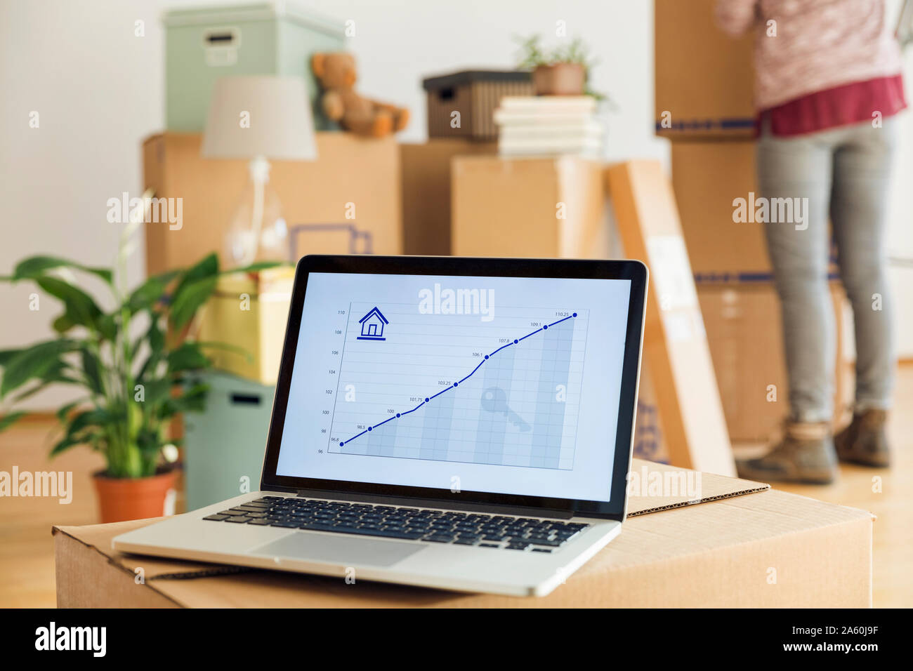 Rising line graph on laptop screen in front of cardboard boxes in a new ...