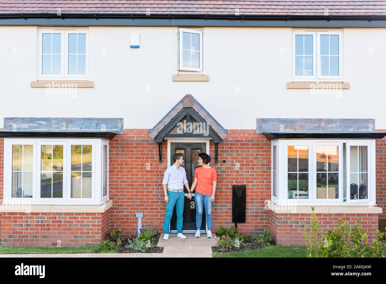 Couple standing at doorstep of their home Stock Photo - Alamy