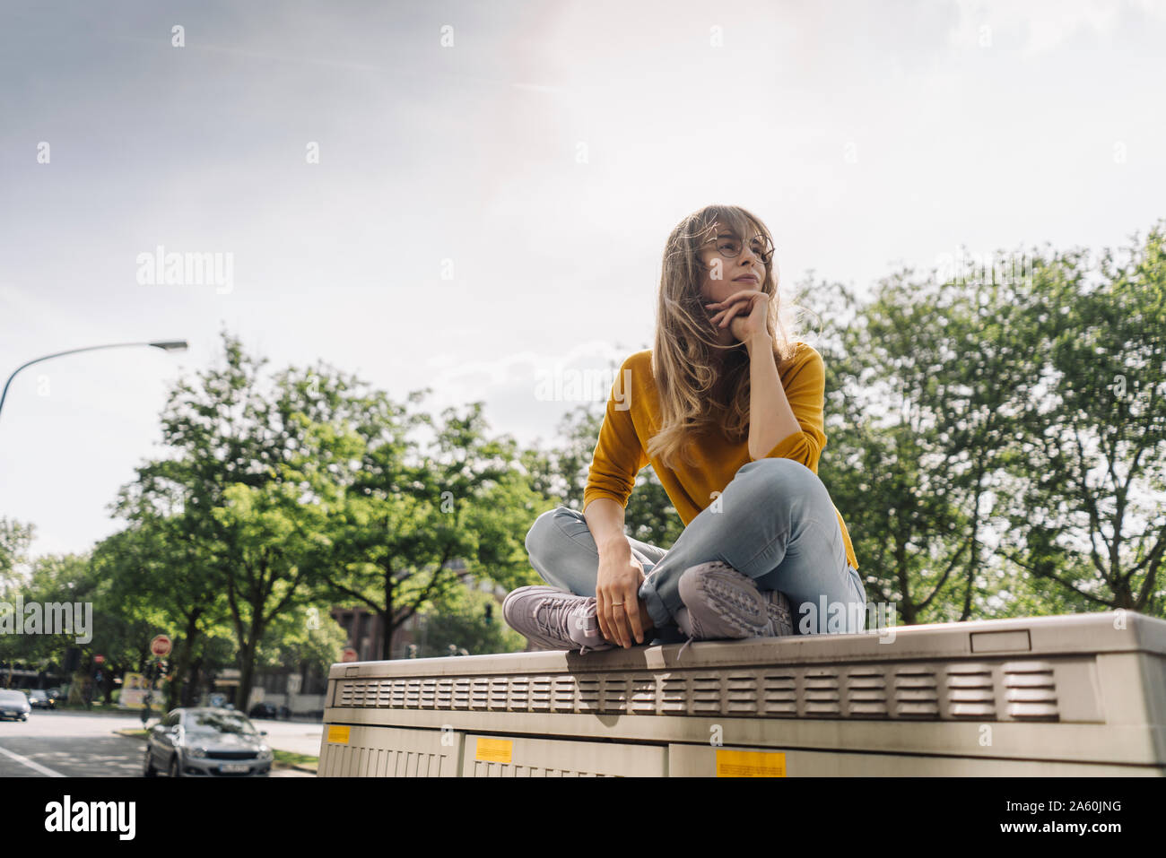 Young woman sitting on a box in the city Stock Photo - Alamy