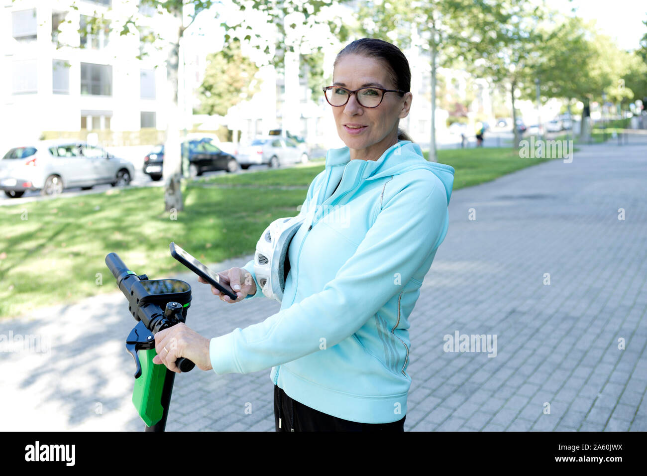 Portrait of mature woman scanning QR Code for activating rental ...