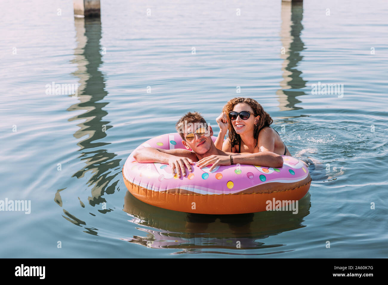 Young couple bathing in the sea on inflatable float in donut shape ...