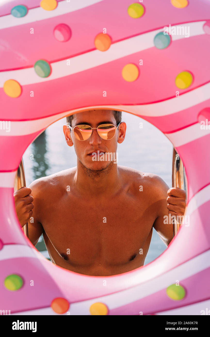 Portrait of young man behind inflatable float in donut shape Stock ...