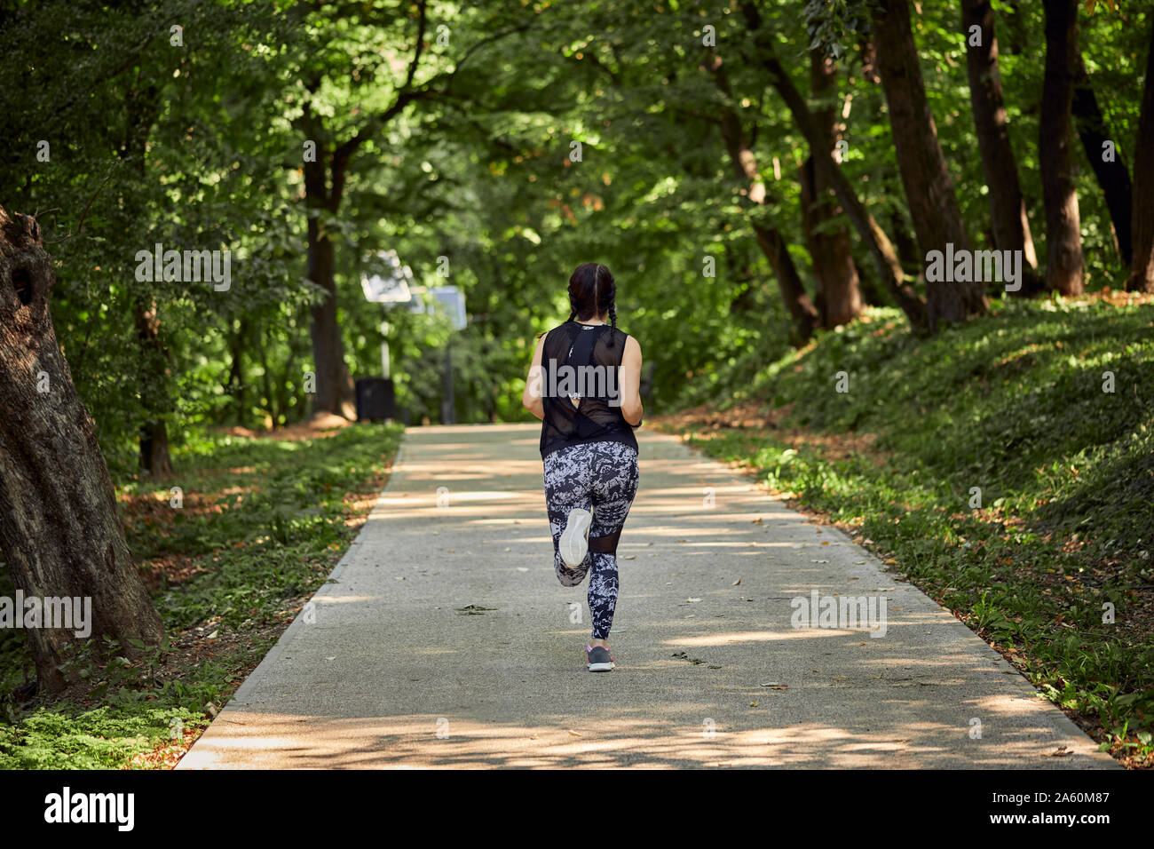 Rear view of sporty young woman running on forest path Stock Photo - Alamy