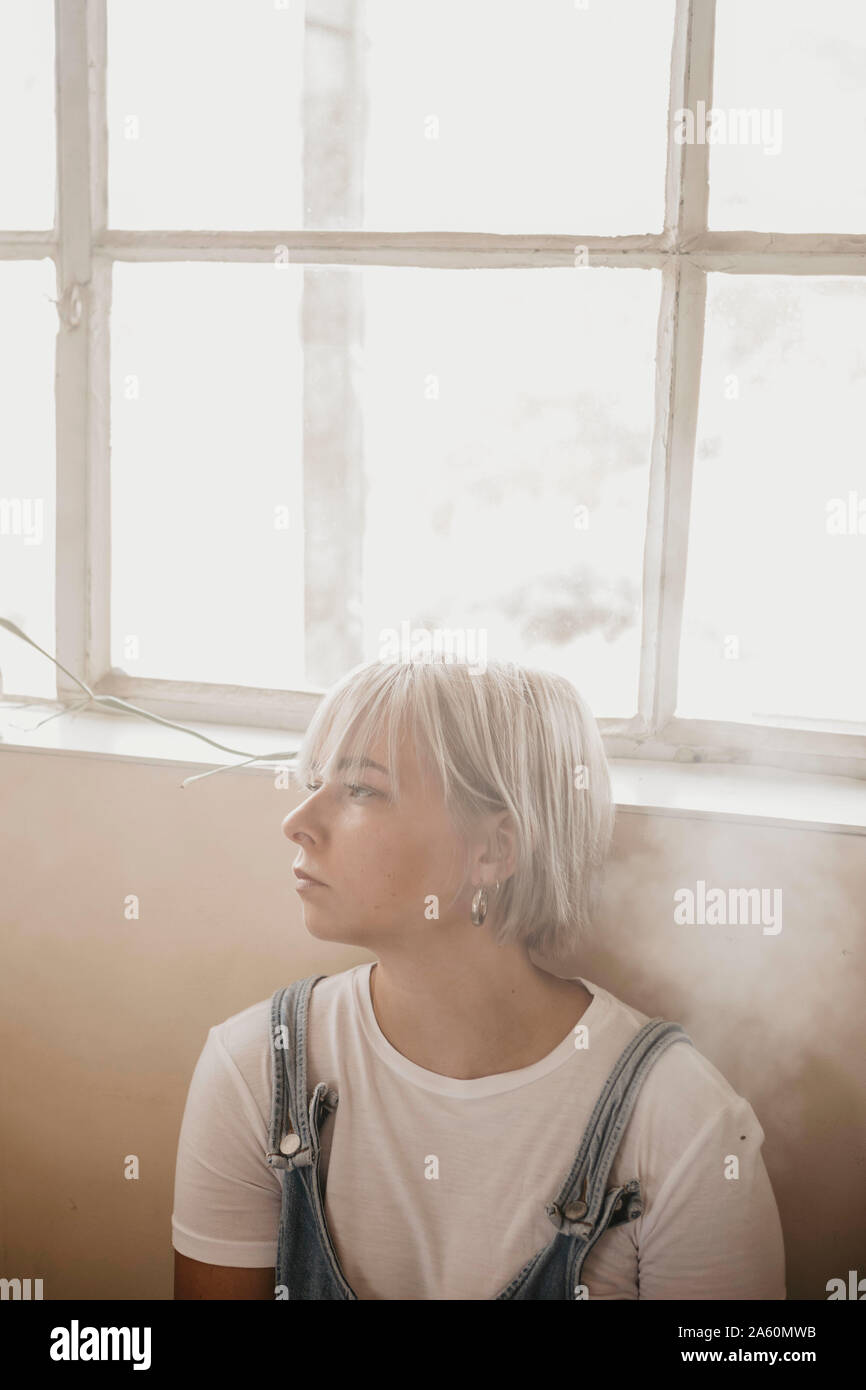 Young woman leaning against a wall under the window Stock Photo - Alamy