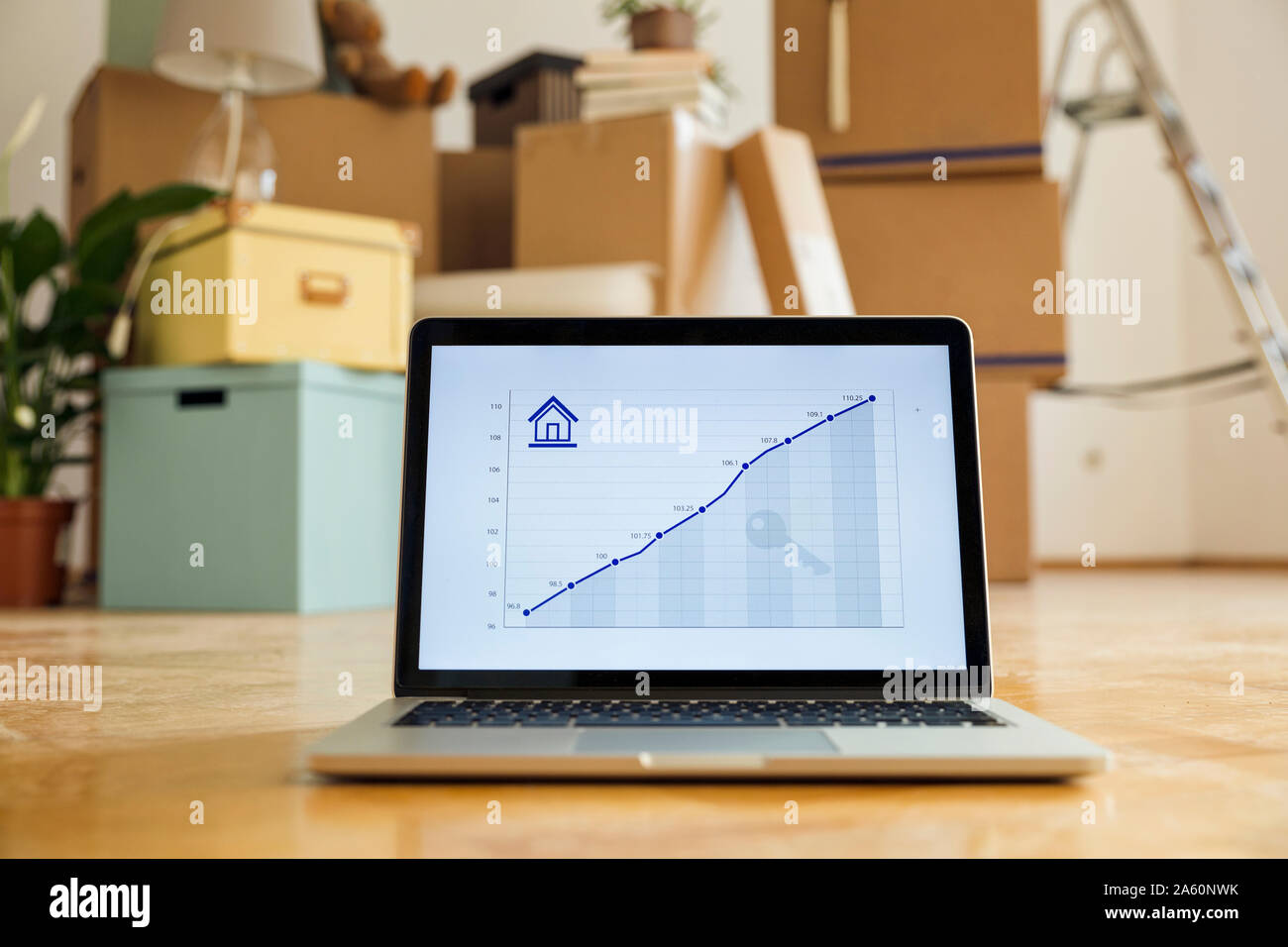 Rising line graph on laptop screen in front of cardboard boxes in an ...