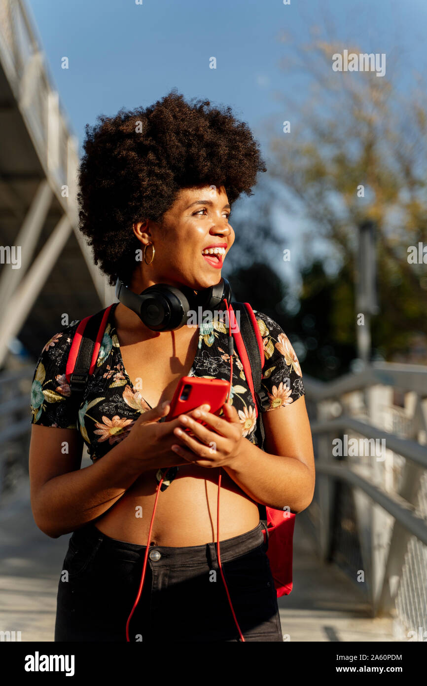 Female Afro-American with headphones and smartphone listening music ...