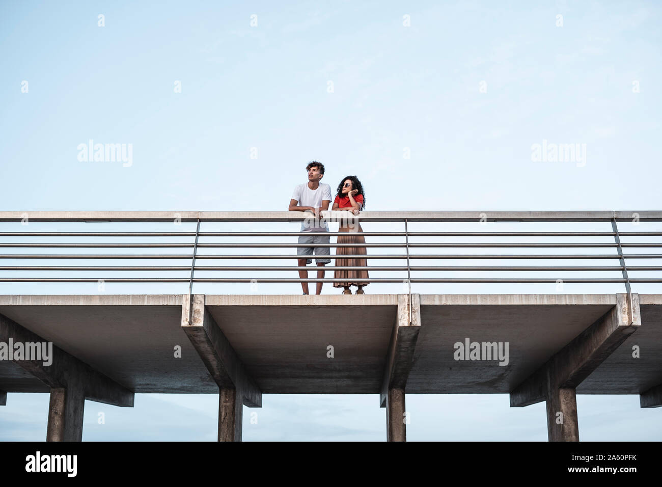 Young couple standing on bridge, looking at view Stock Photo - Alamy