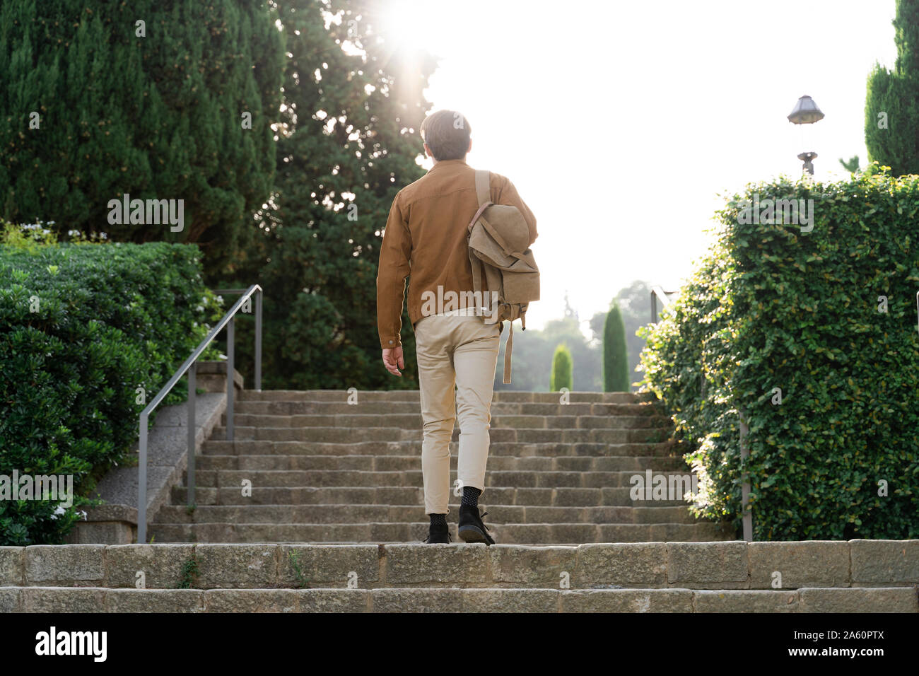 Back view of man with backpack walking upstairs Stock Photo - Alamy
