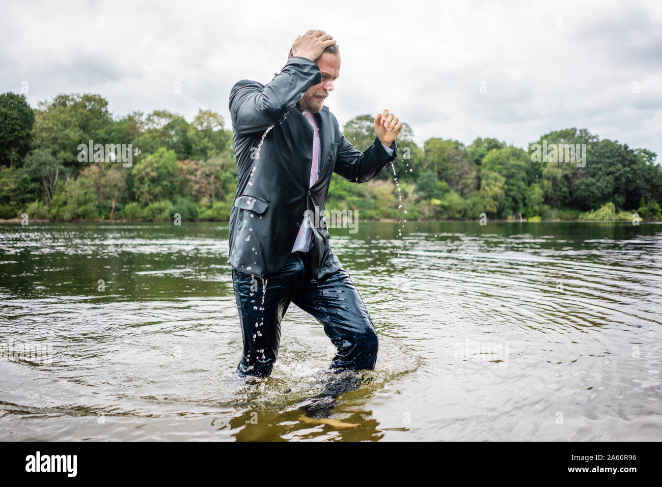 Wet businessman walking in a lake Stock Photo - Alamy