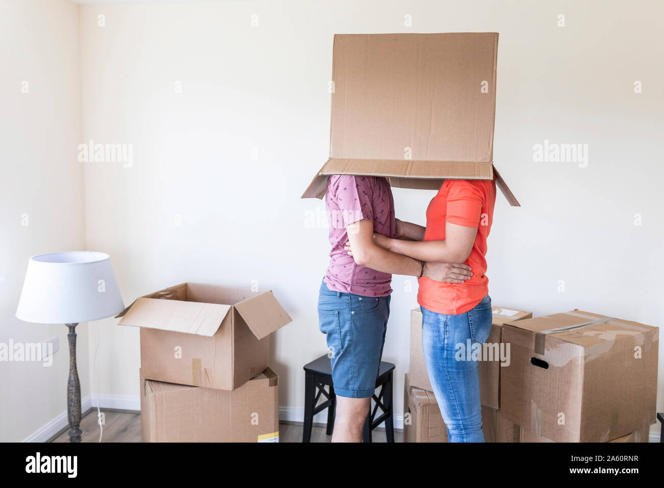 Couple moving into new home hiding under cardboard box Stock Photo - Alamy
