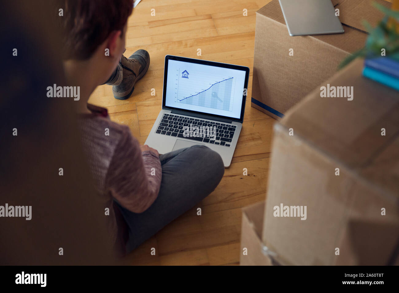 Woman using laptop with rising line graph on the screen in a new home ...