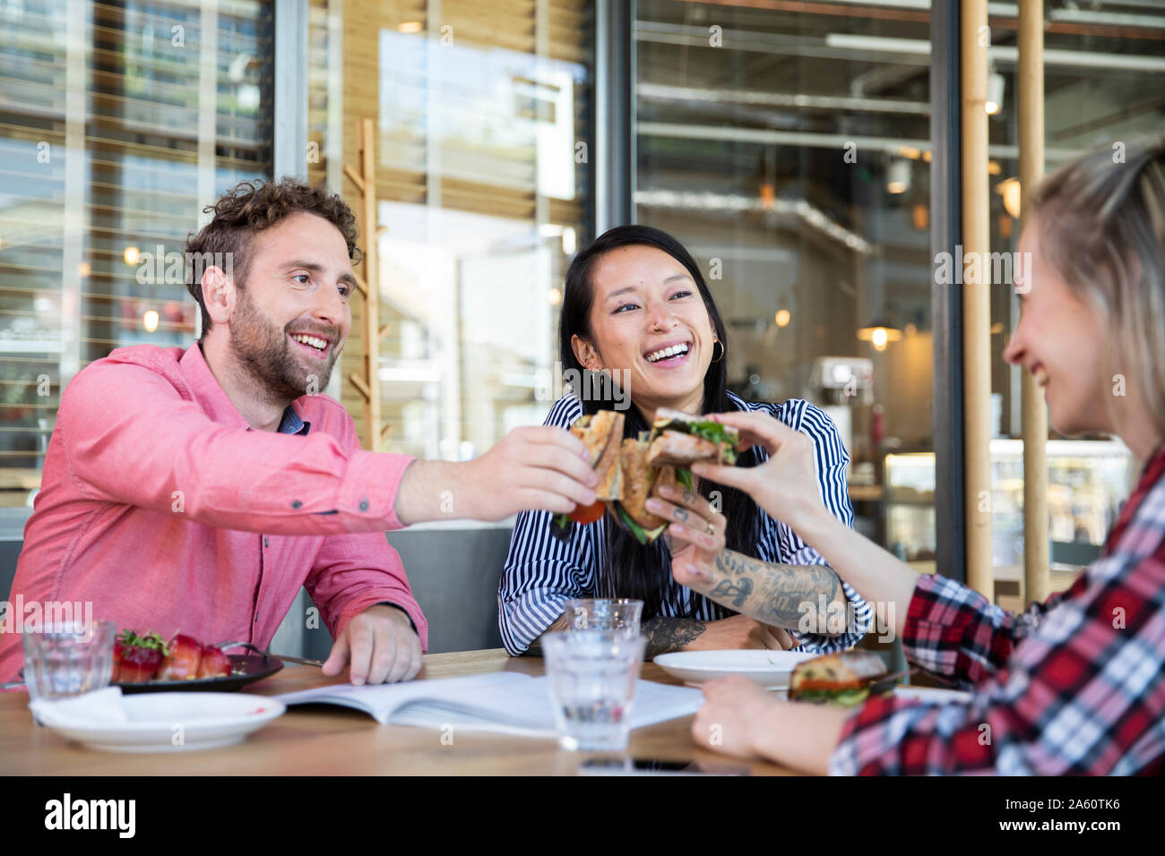 Happy friends having lunch in a cafe Stock Photo - Alamy