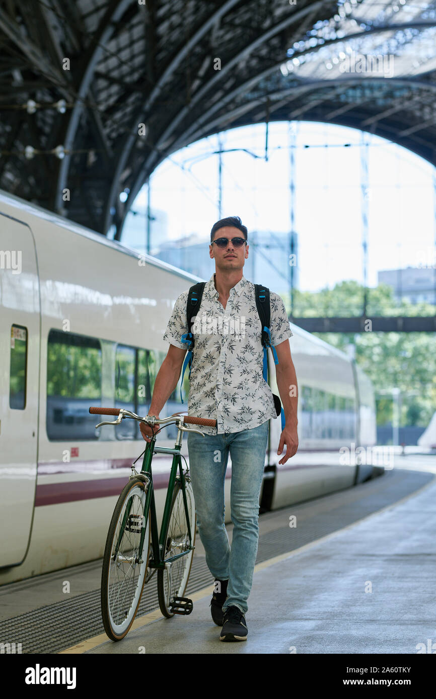 Man pushing bicycle through a station Stock Photo - Alamy