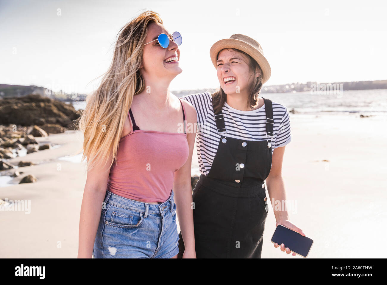 Two girlfriends having fun, walking on the beach Stock Photo - Alamy