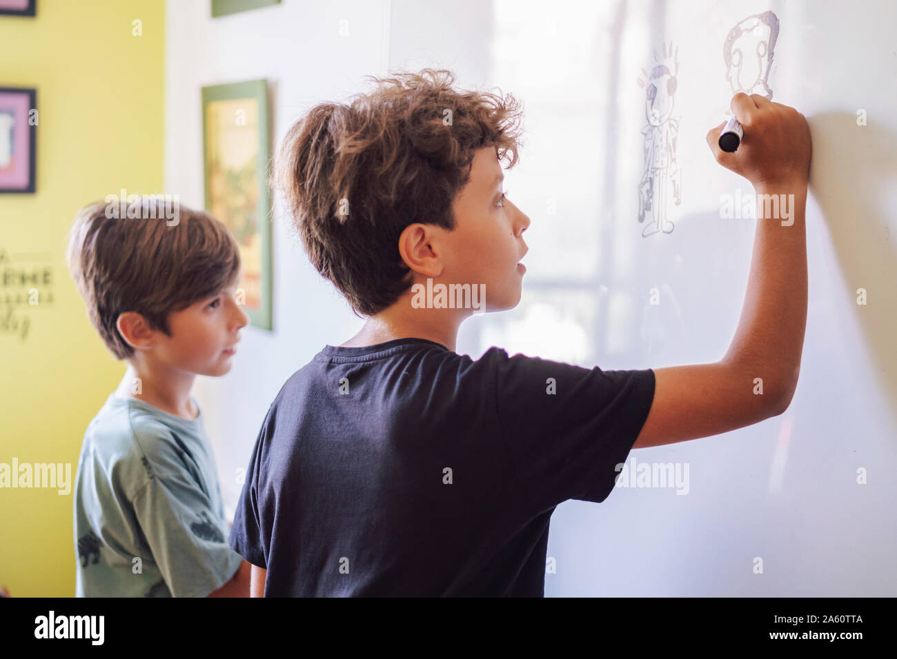 Focused boy with a friend drawing on a whiteboard Stock Photo - Alamy