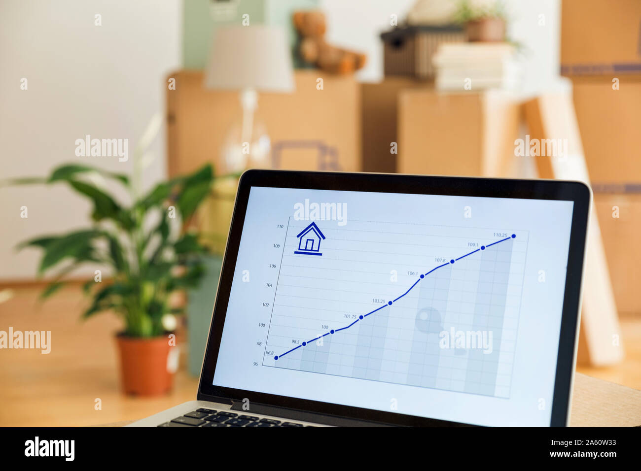Rising line graph on laptop screen in front of cardboard boxes in a new ...