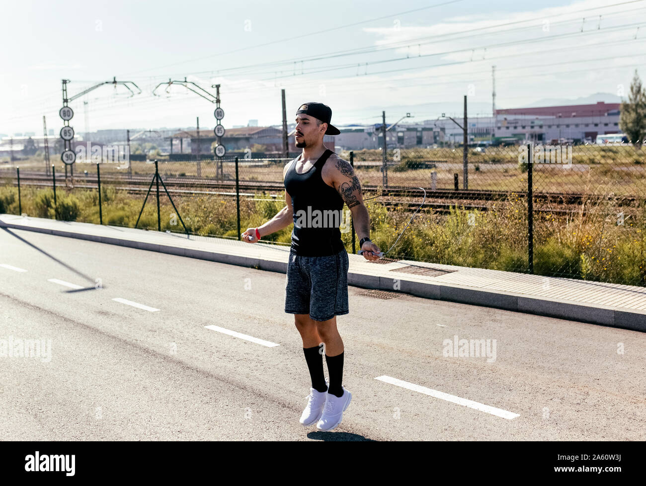 Young man skipping rope on a road Stock Photo - Alamy