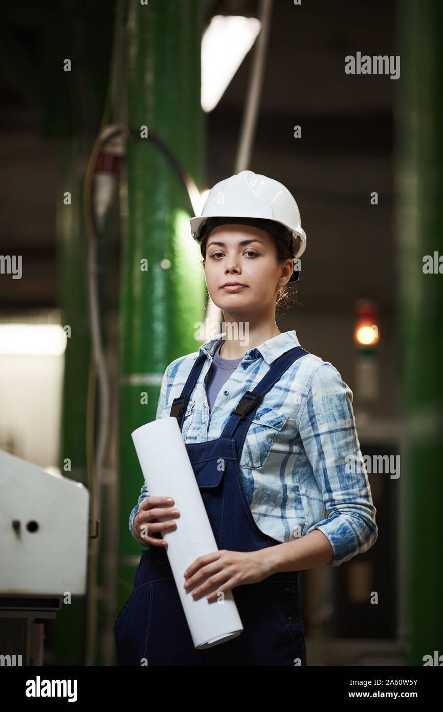 Portrait of confident female engineer in overalls and in work helmet ...