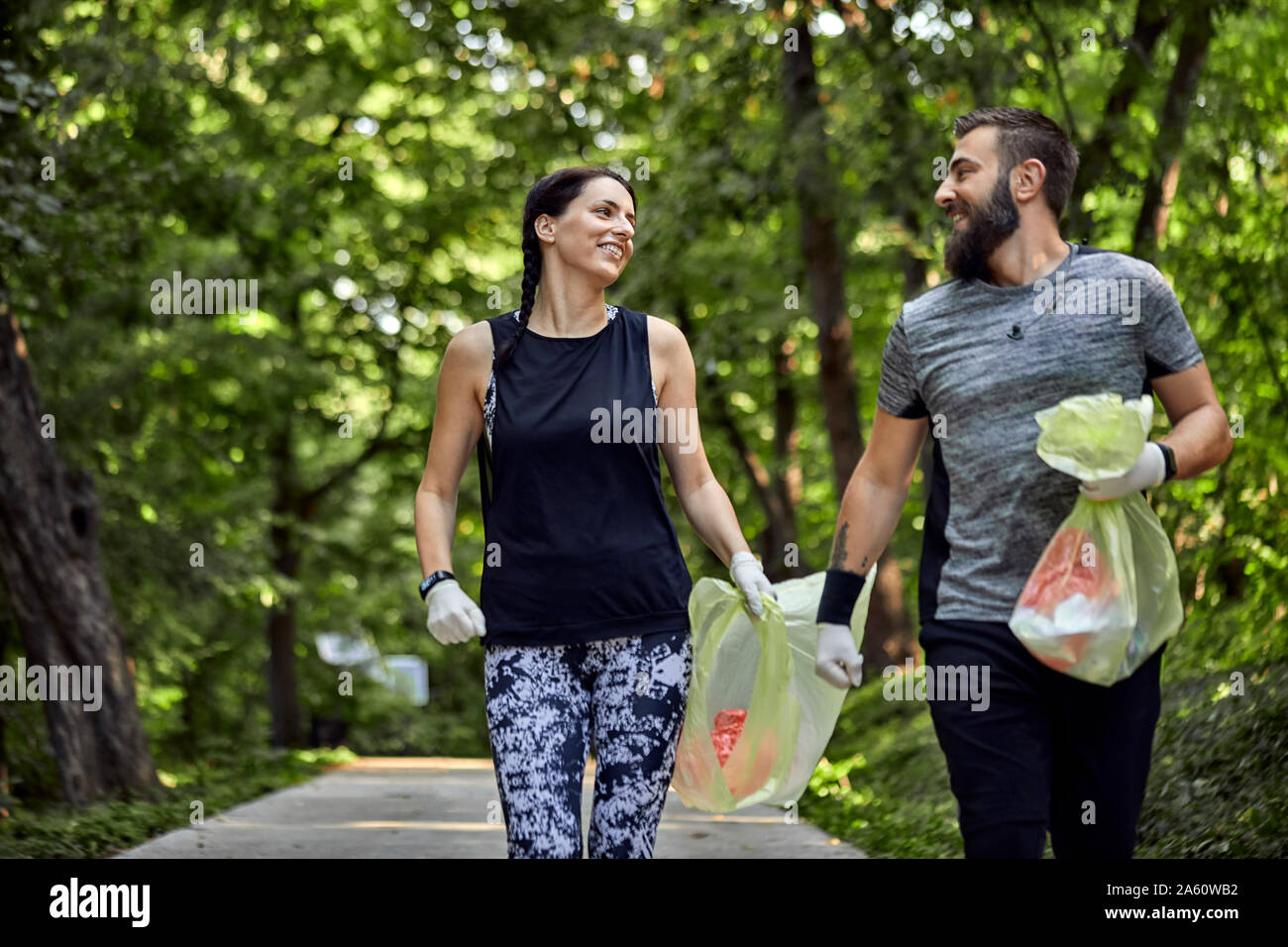 Couple plogging on forest path Stock Photo - Alamy