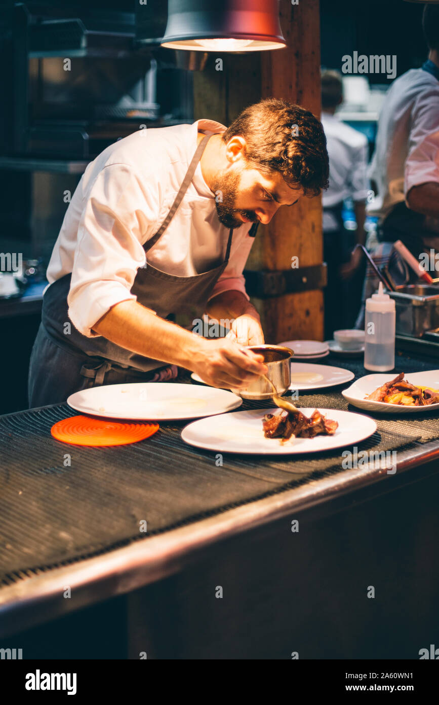Chef serving food on plates in the kitchen of a restaurant Stock Photo ...