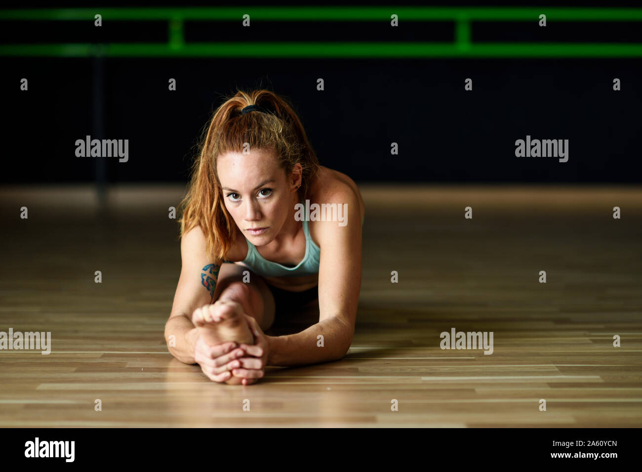 Sporty young woman stretching in exercise room Stock Photo - Alamy