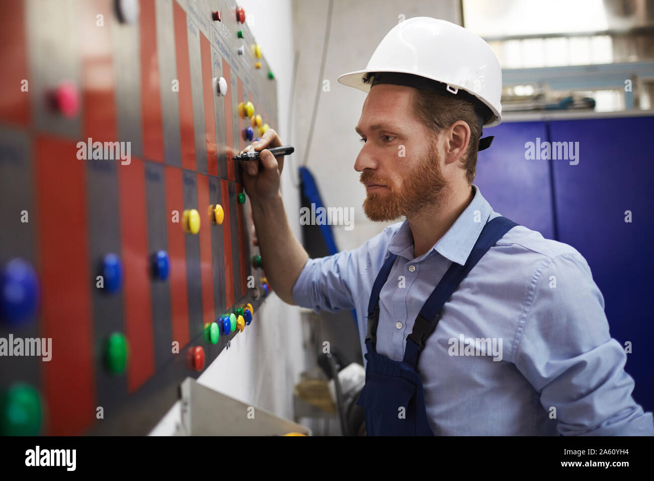 Foreman in work wear standing near the blackboard and making the ...