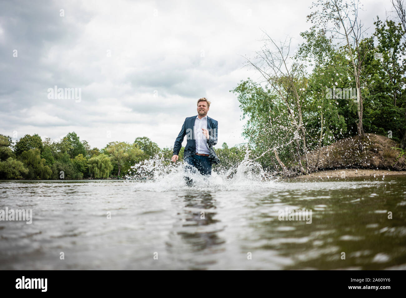 Businessman running through a lake Stock Photo - Alamy