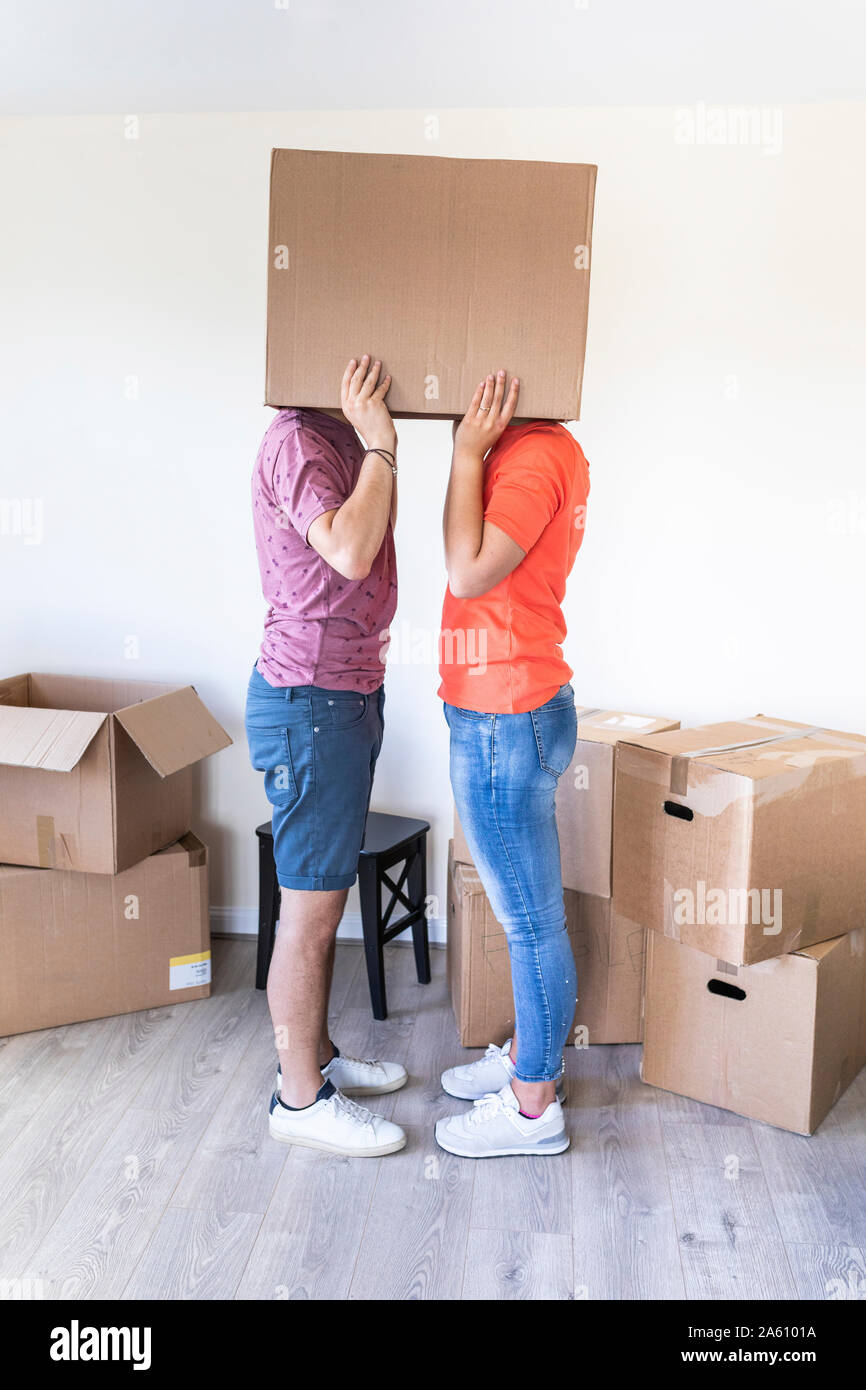 Couple moving into new home hiding under cardboard box Stock Photo - Alamy
